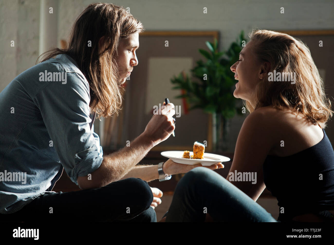Side view of couple eating together while sitting at home Stock Photo ...