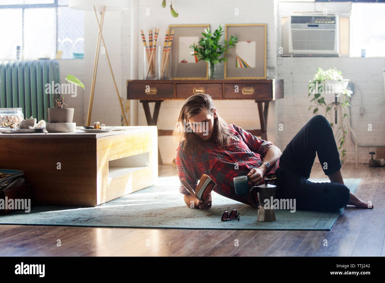 Man reading book while leaning on elbow at home Stock Photo - Alamy