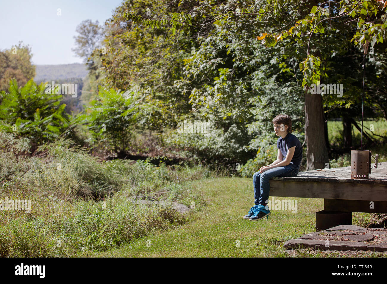 Boy sitting on porch by forest Stock Photo - Alamy