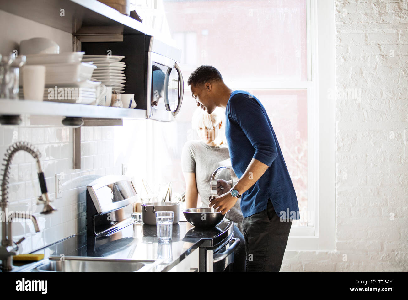 Multi-ethnic couple cooking in kitchen Stock Photo - Alamy