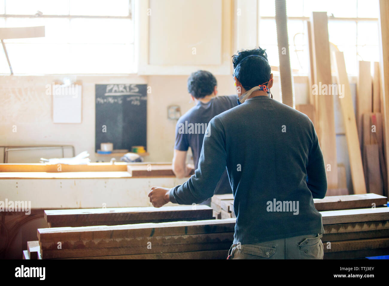 Rear view of male carpenters working in workshop Stock Photo - Alamy