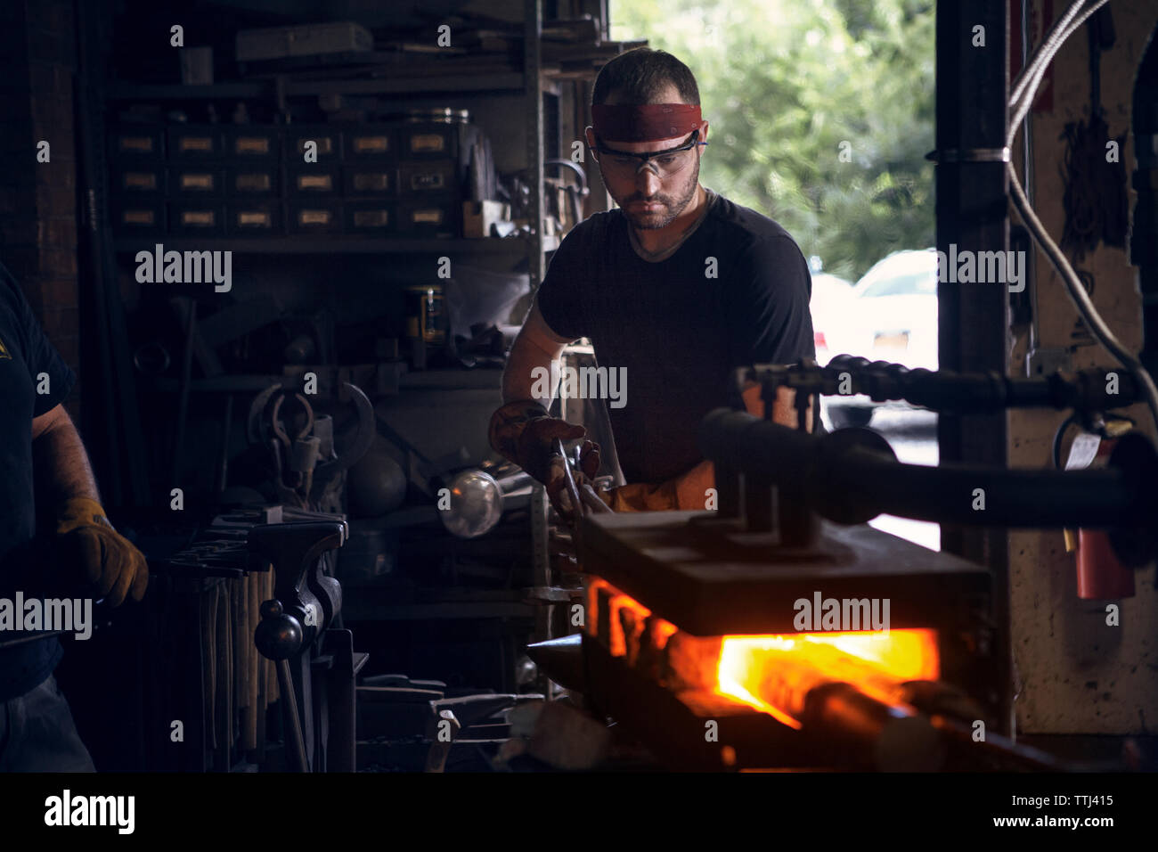 Blacksmith shaping rod with coworker at workshop Stock Photo - Alamy