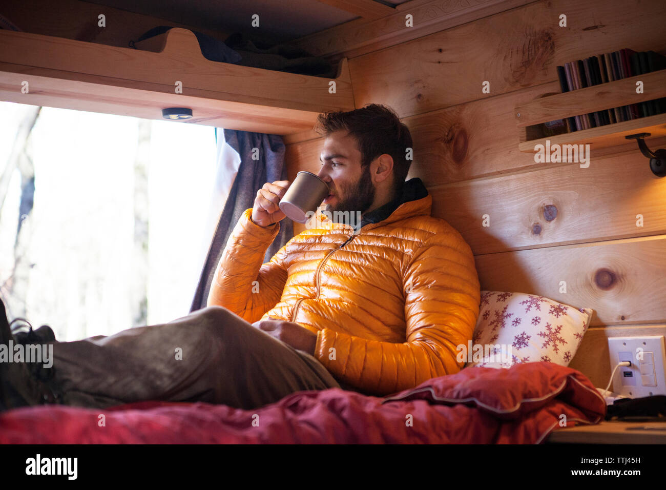 Man having drink while sitting in camper van Stock Photo - Alamy