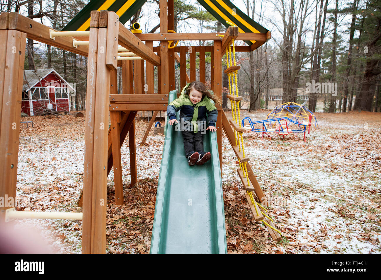 Full length of boy sliding on slide at park Stock Photo - Alamy