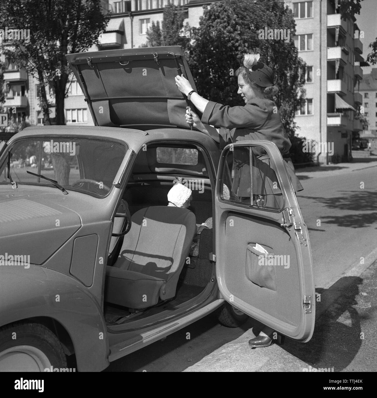 Driving in the 1950s. A young woman in her Fiat convertible car. Note ...