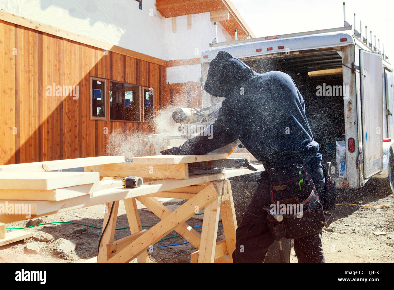 worker cutting wooden planks with circular saw at construction site ...