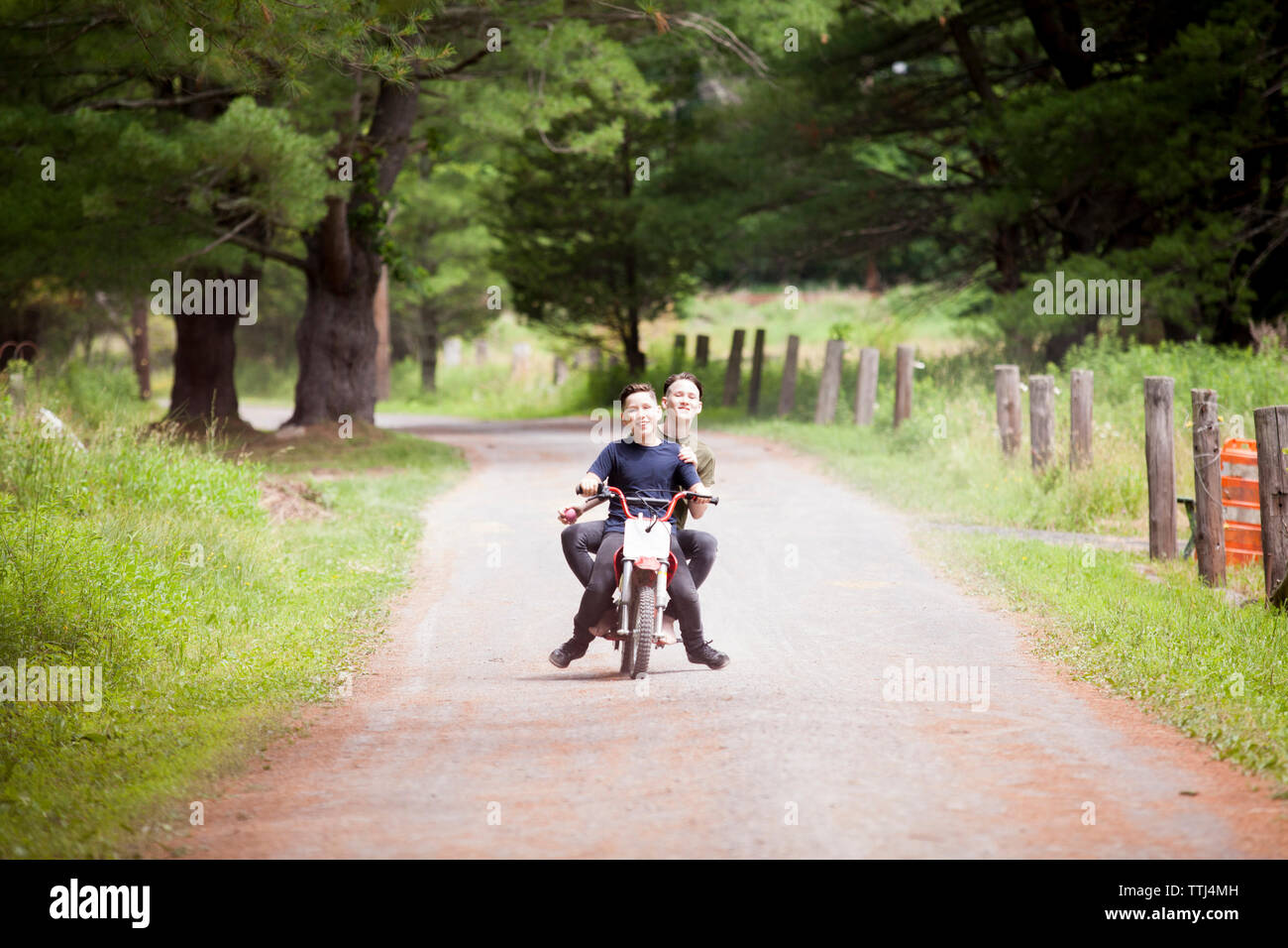 Brothers riding dirt bike on road Stock Photo - Alamy