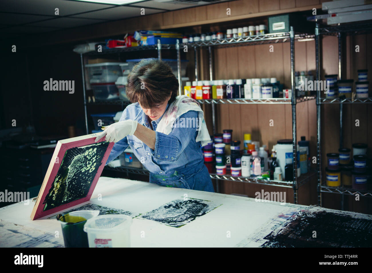 Craftswoman examining ink prints on workbench at workshop Stock Photo ...