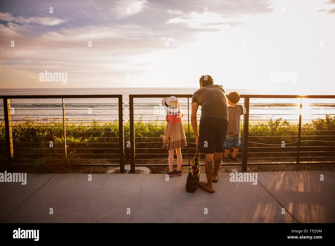 Rear view of family looking at sea while standing by railing during ...