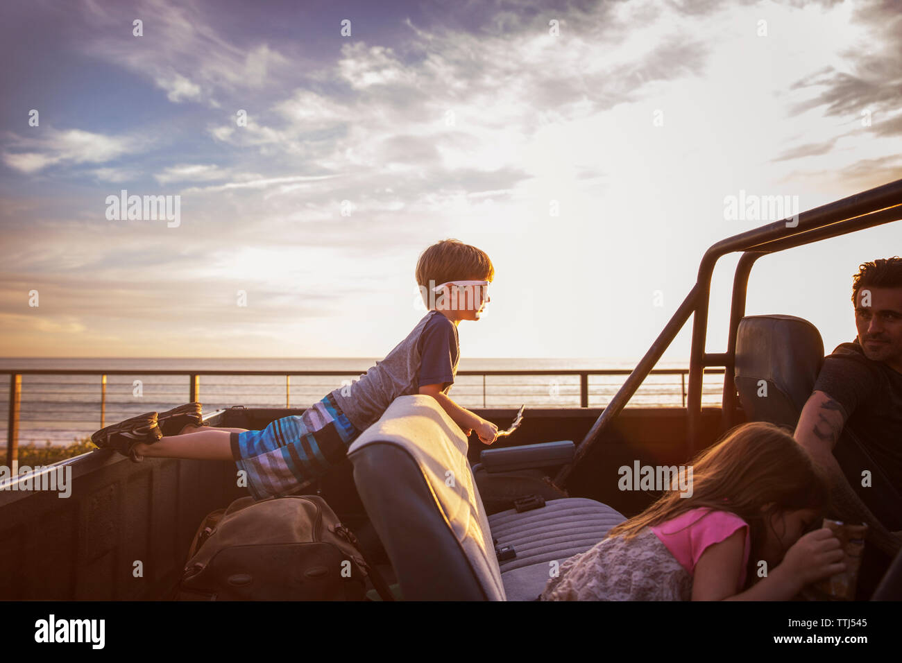 Family in pick-up truck by sea during sunset Stock Photo - Alamy