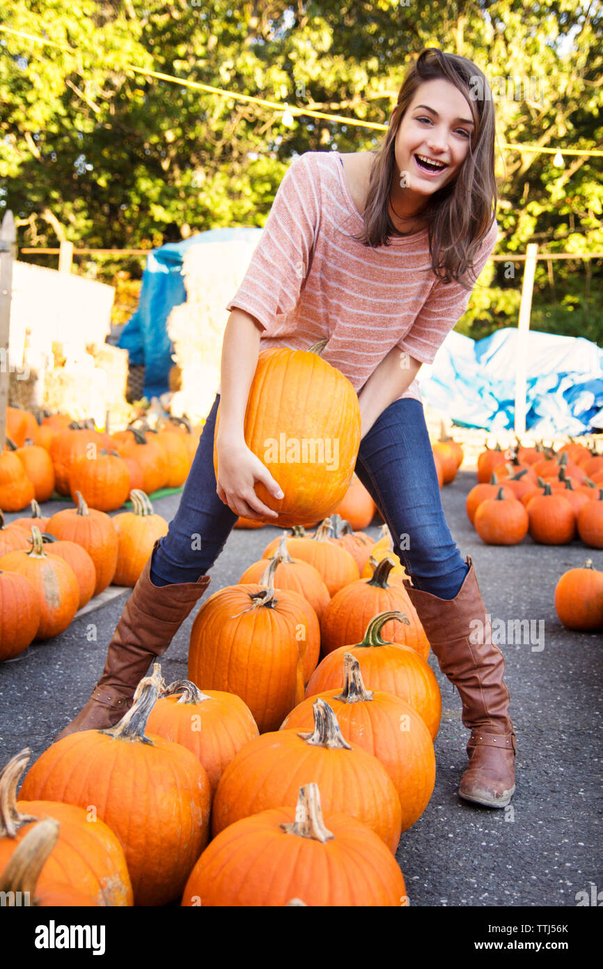 Portrait of happy woman carrying pumpkin at market stall Stock Photo ...