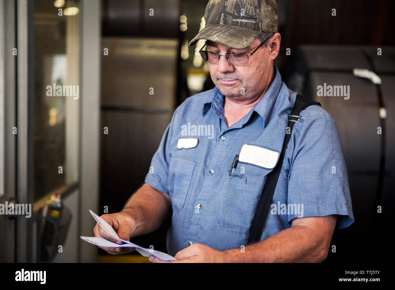 Serious worker examining documents while standing in metal industry ...