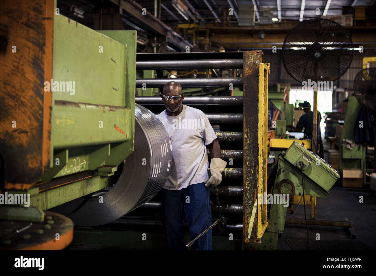 Manual worker working at machinery in metal industry Stock Photo - Alamy