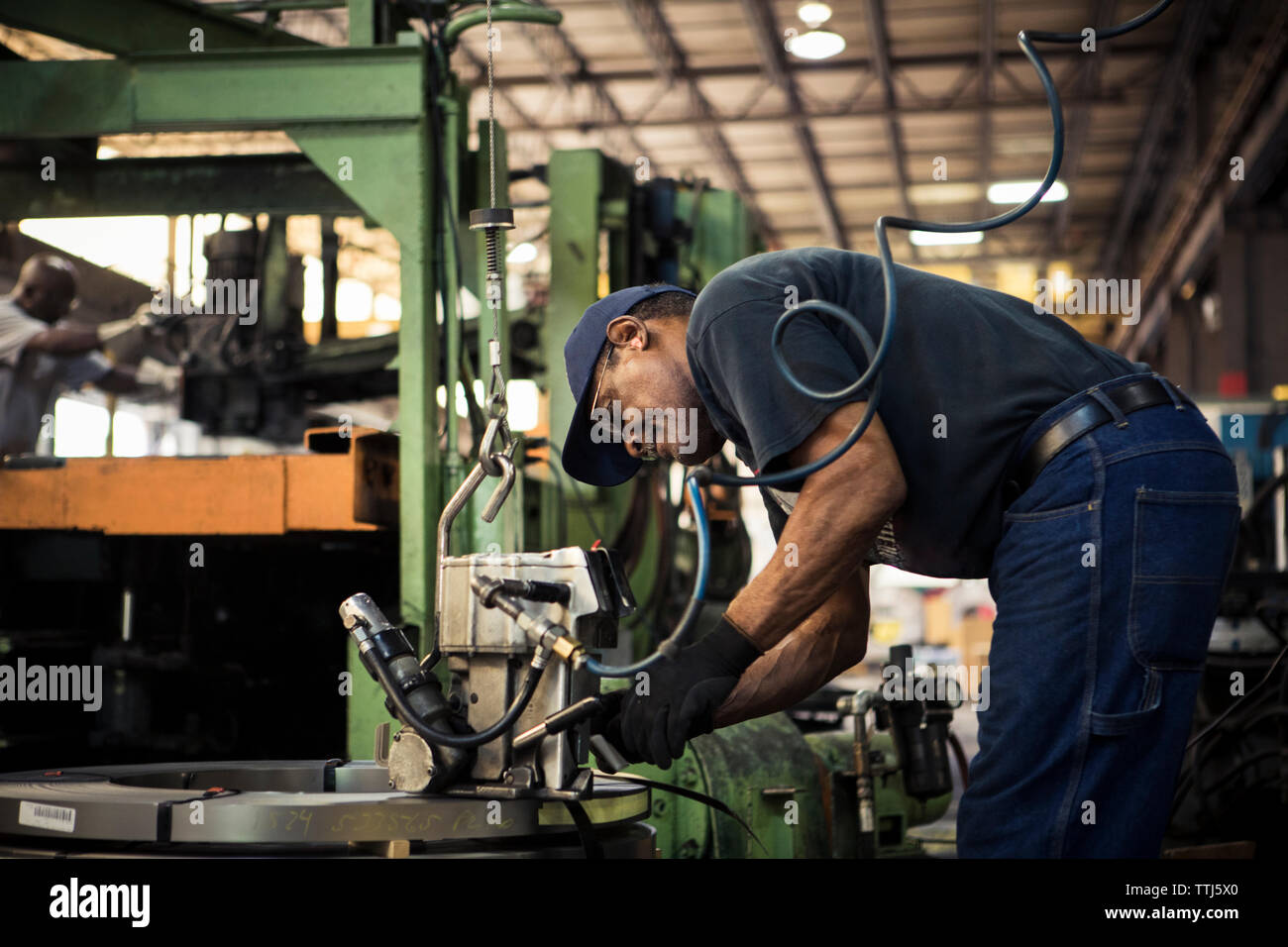 Side view of manual worker using machinery while working in metal ...