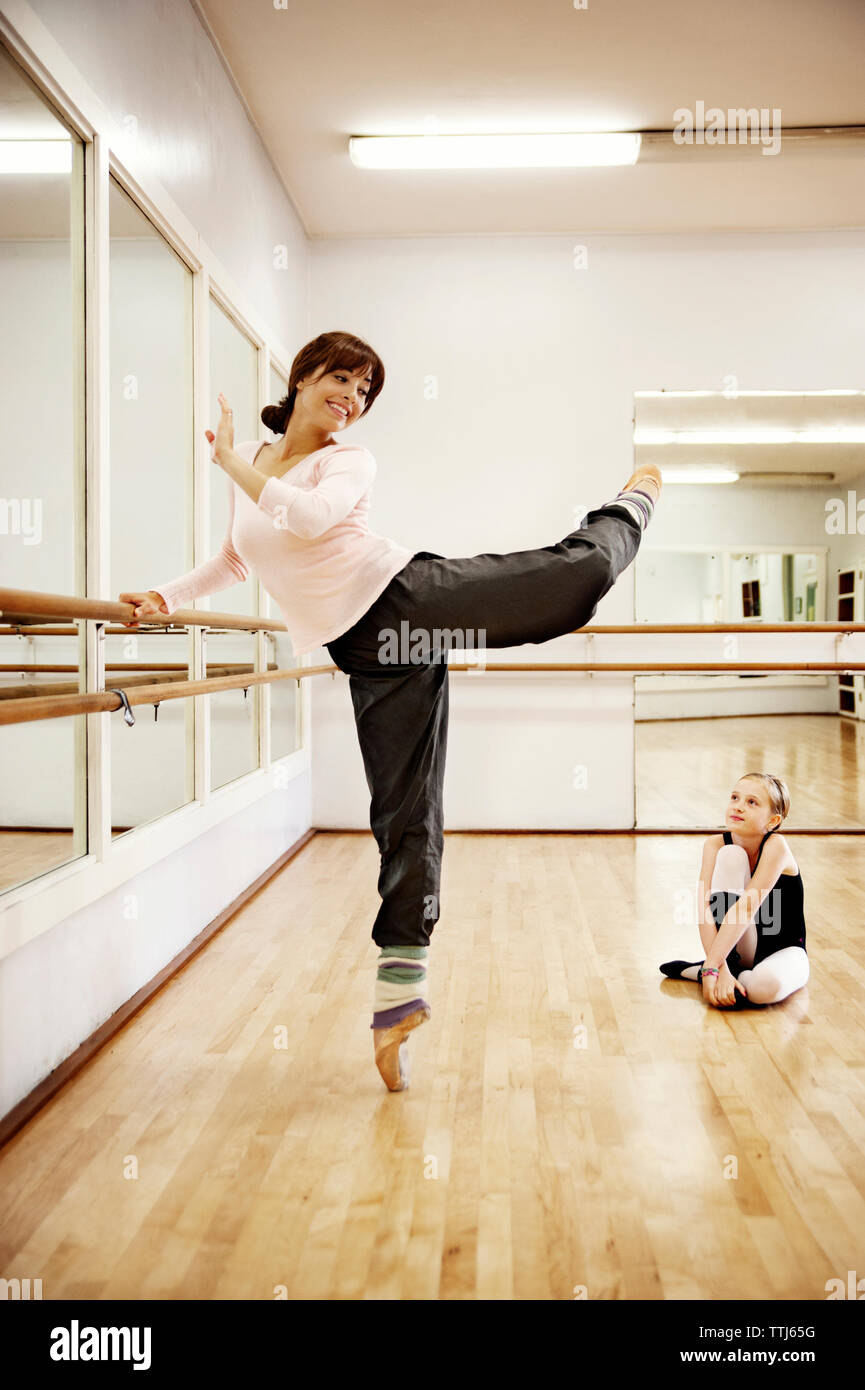 Girl looking at teacher dancing while sitting on floor Stock Photo - Alamy