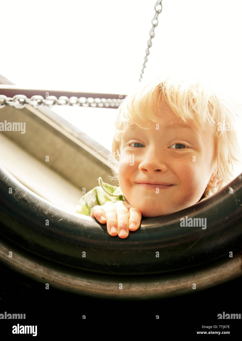 Portrait of happy boy looking through tire swing Stock Photo - Alamy