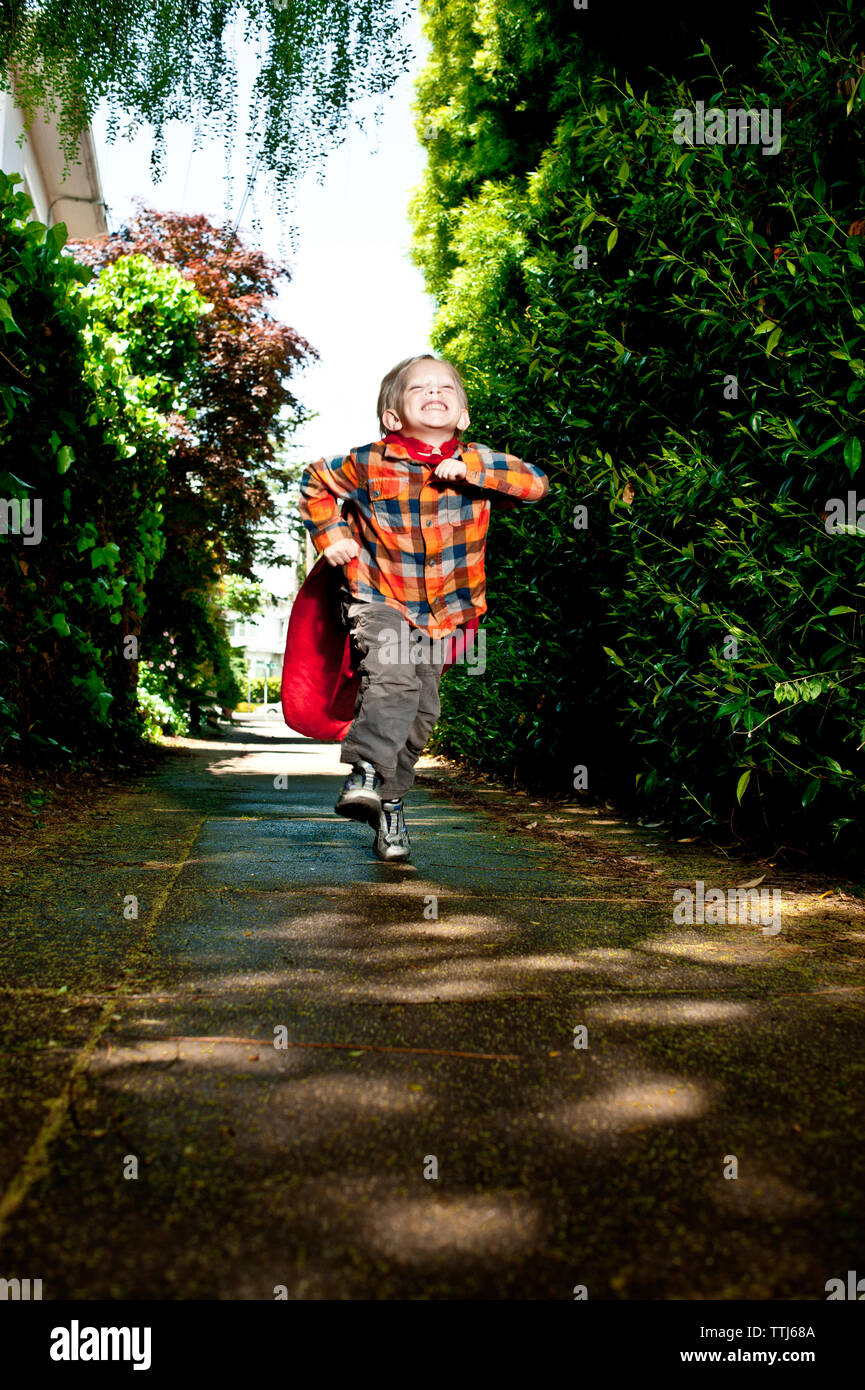 Cheerful boy wearing cape running at backyard Stock Photo - Alamy