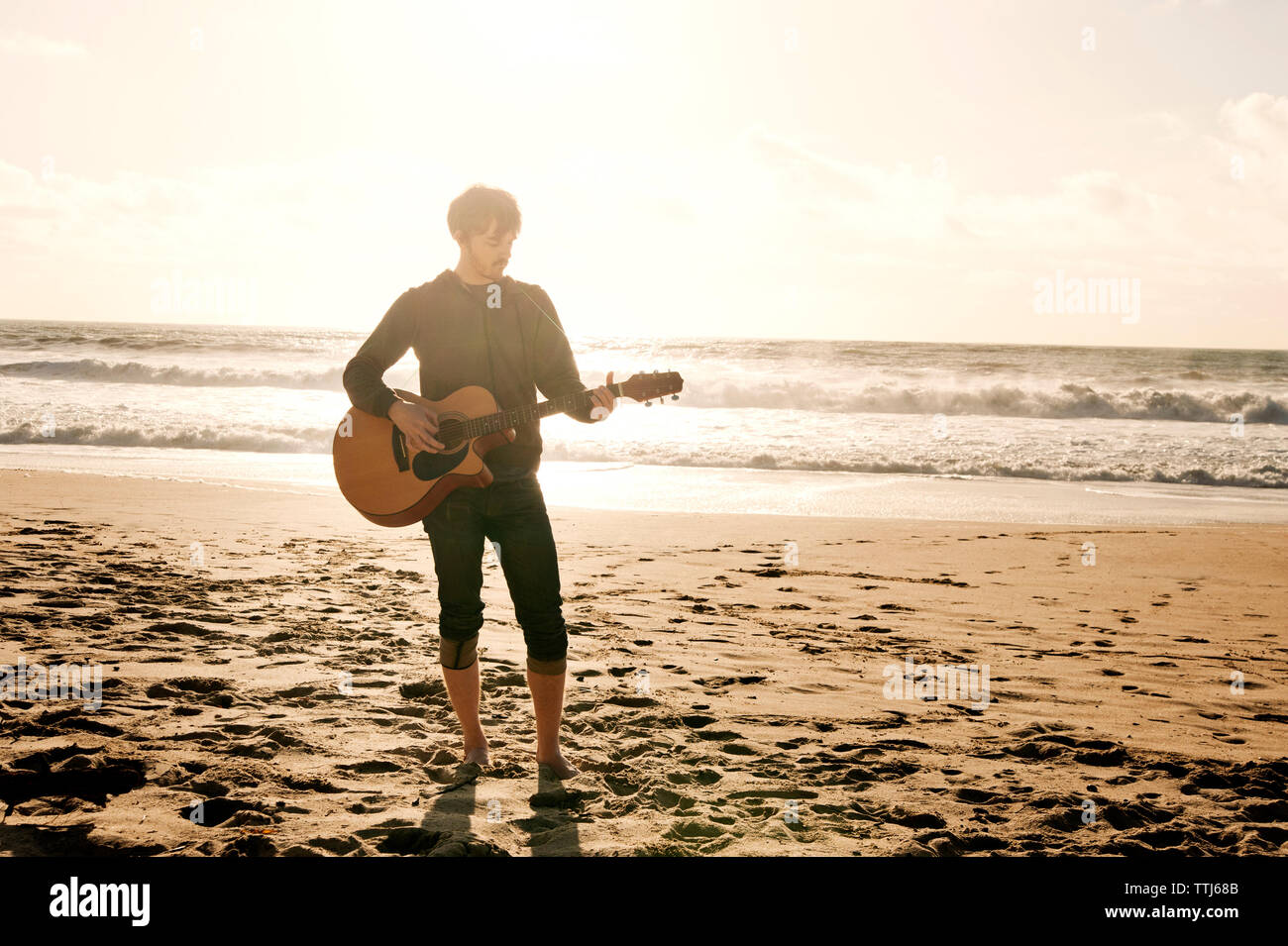 Man playing guitar while standing at beach Stock Photo - Alamy