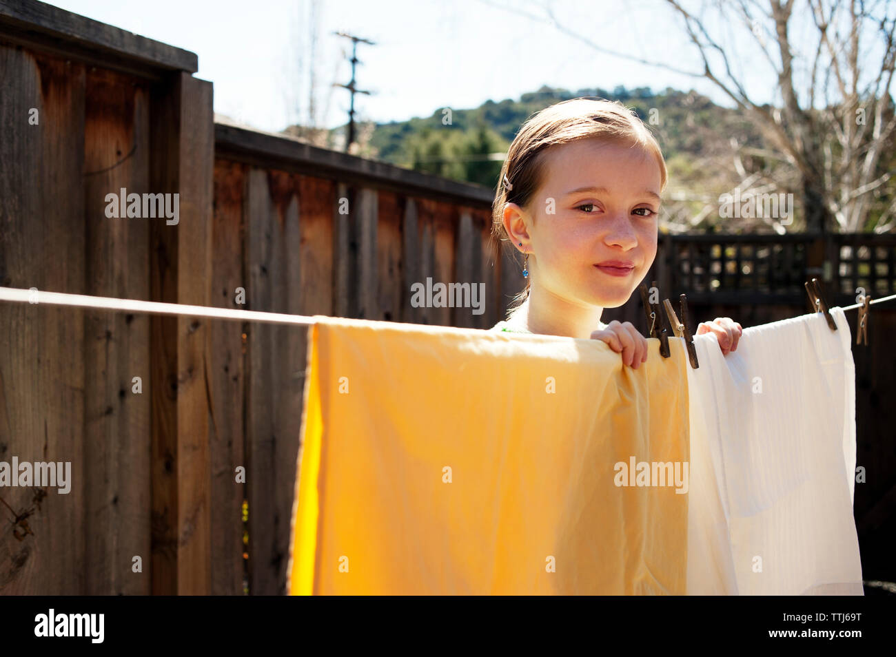 Portrait of girl holding clothesline while standing at backyard Stock ...