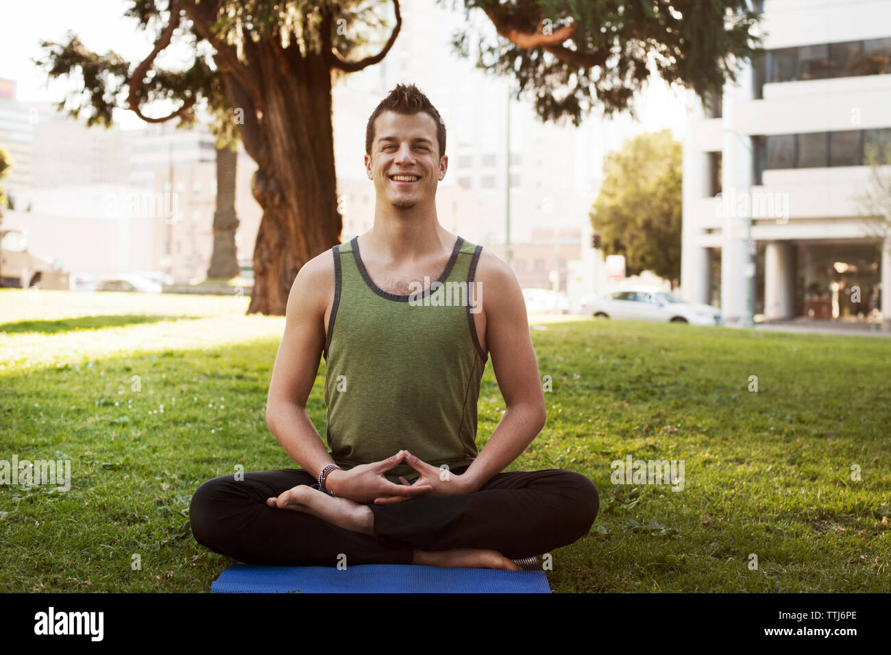 Portrait of man sitting in lotus position on exercise mat at park Stock ...