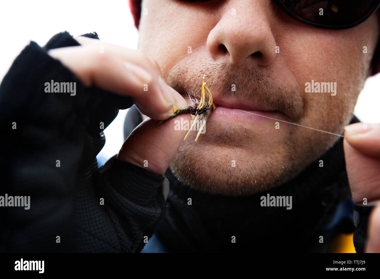Close-up of man Biting thread of hook Stock Photo - Alamy