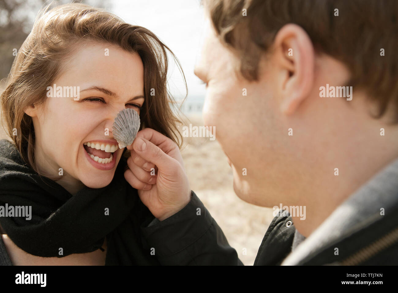 Man holding shell on woman nose while standing at beach Stock Photo - Alamy