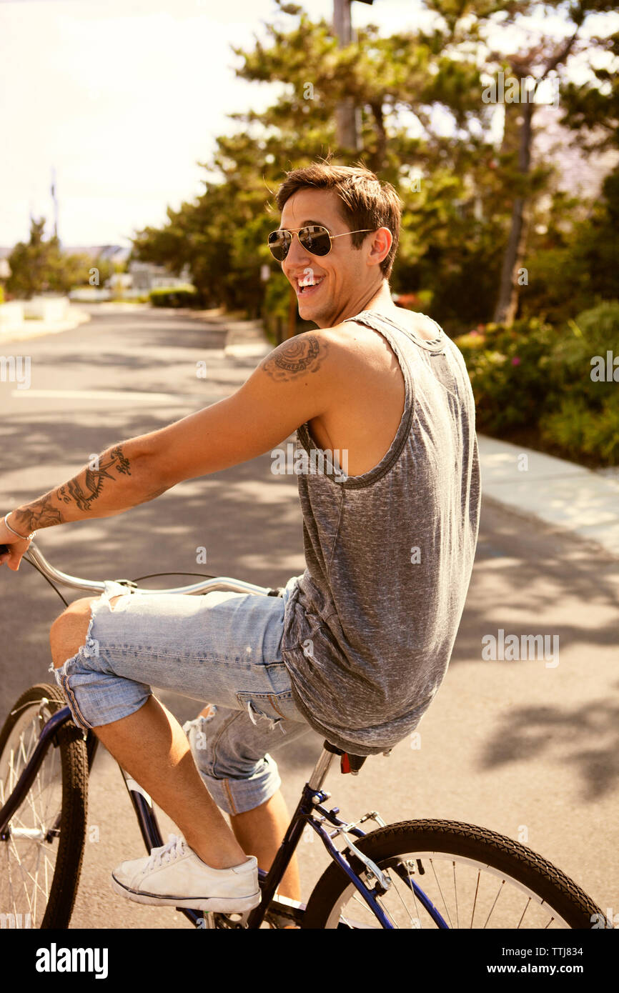 Side view of happy man riding bicycle on road Stock Photo - Alamy