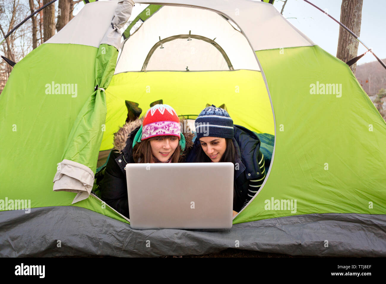 Friends using laptop computer while lying in tent Stock Photo - Alamy