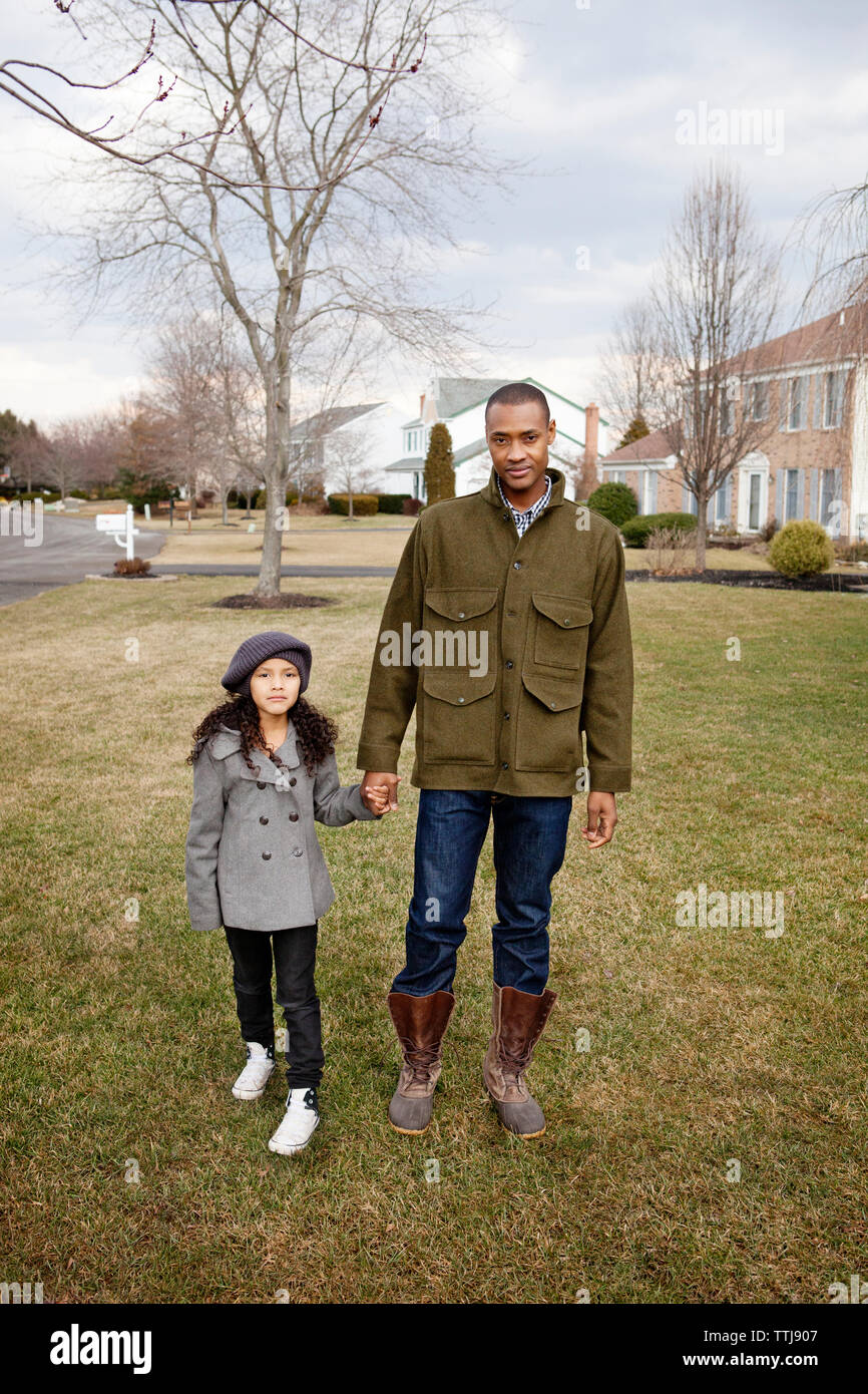 Portrait of father and daughter holding hands while standing in ...