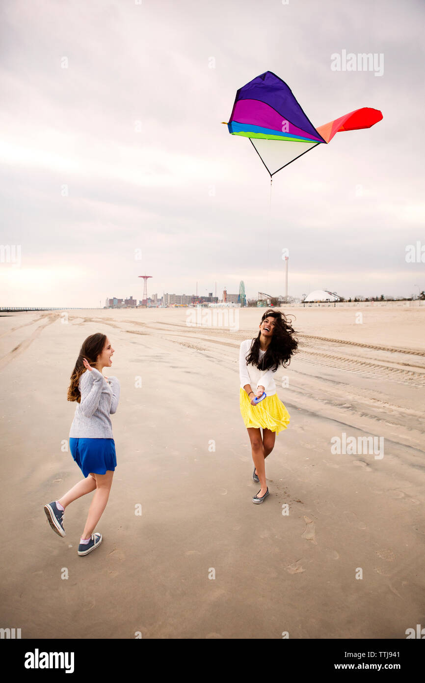 Happy friends flying kite at beach Stock Photo - Alamy