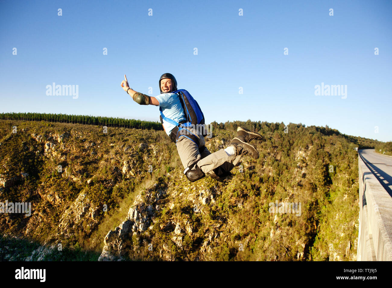 Side view of man base jumping against clear sky Stock Photo - Alamy