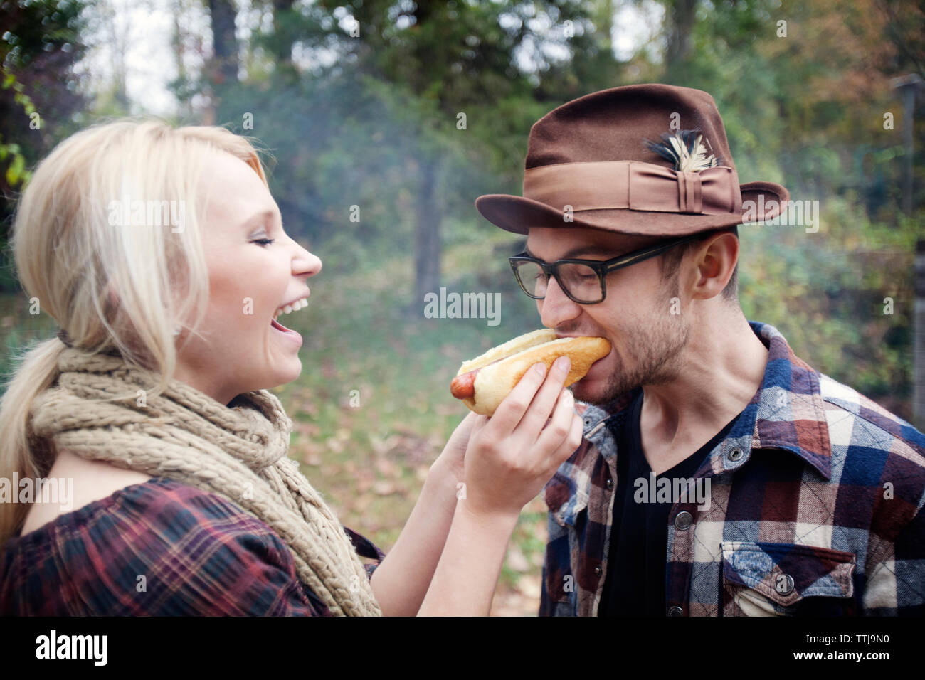Woman feeding man while standing at backyard Stock Photo - Alamy