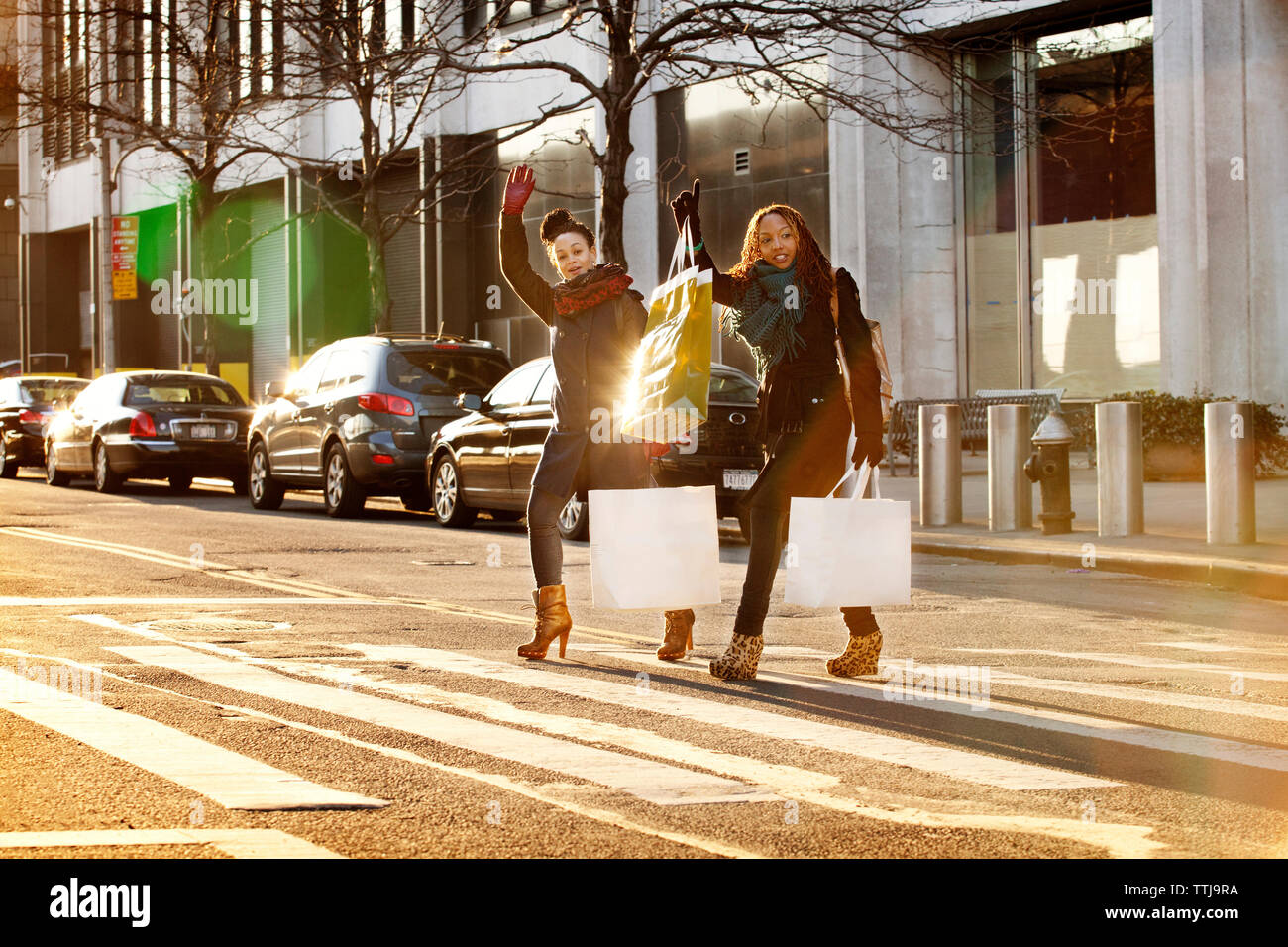 Friends raising arms while crossing road Stock Photo - Alamy