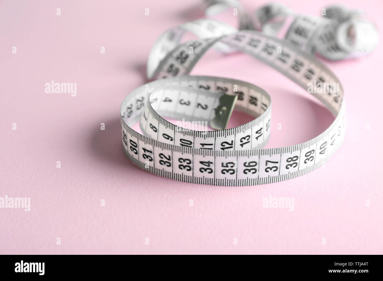 Measuring tape on pink background Stock Photo - Alamy