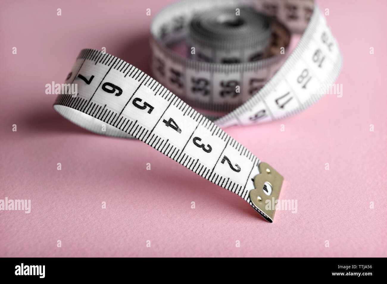 Measuring tape on pink background Stock Photo - Alamy