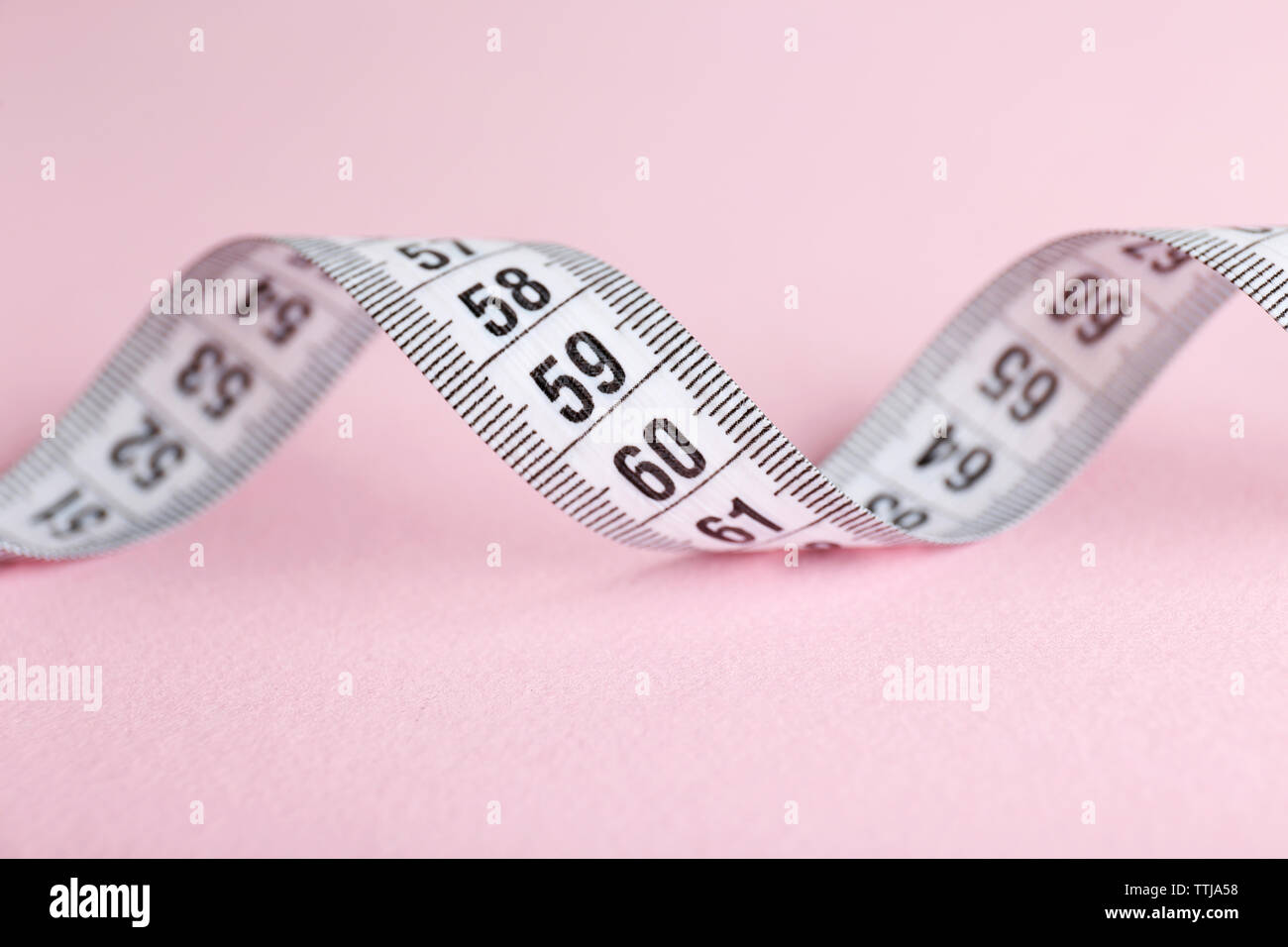 Measuring tape on pink background Stock Photo - Alamy