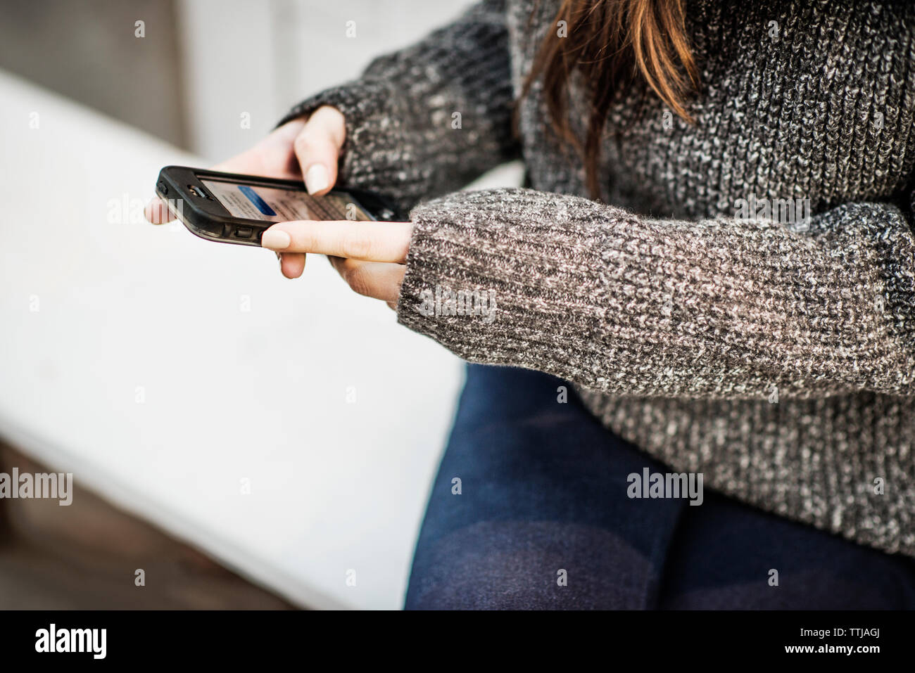 Cropped image of woman using mobile phone while sitting on bench Stock ...