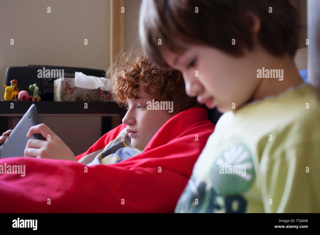 Boy using tablet computer while sitting by brother at home Stock Photo ...