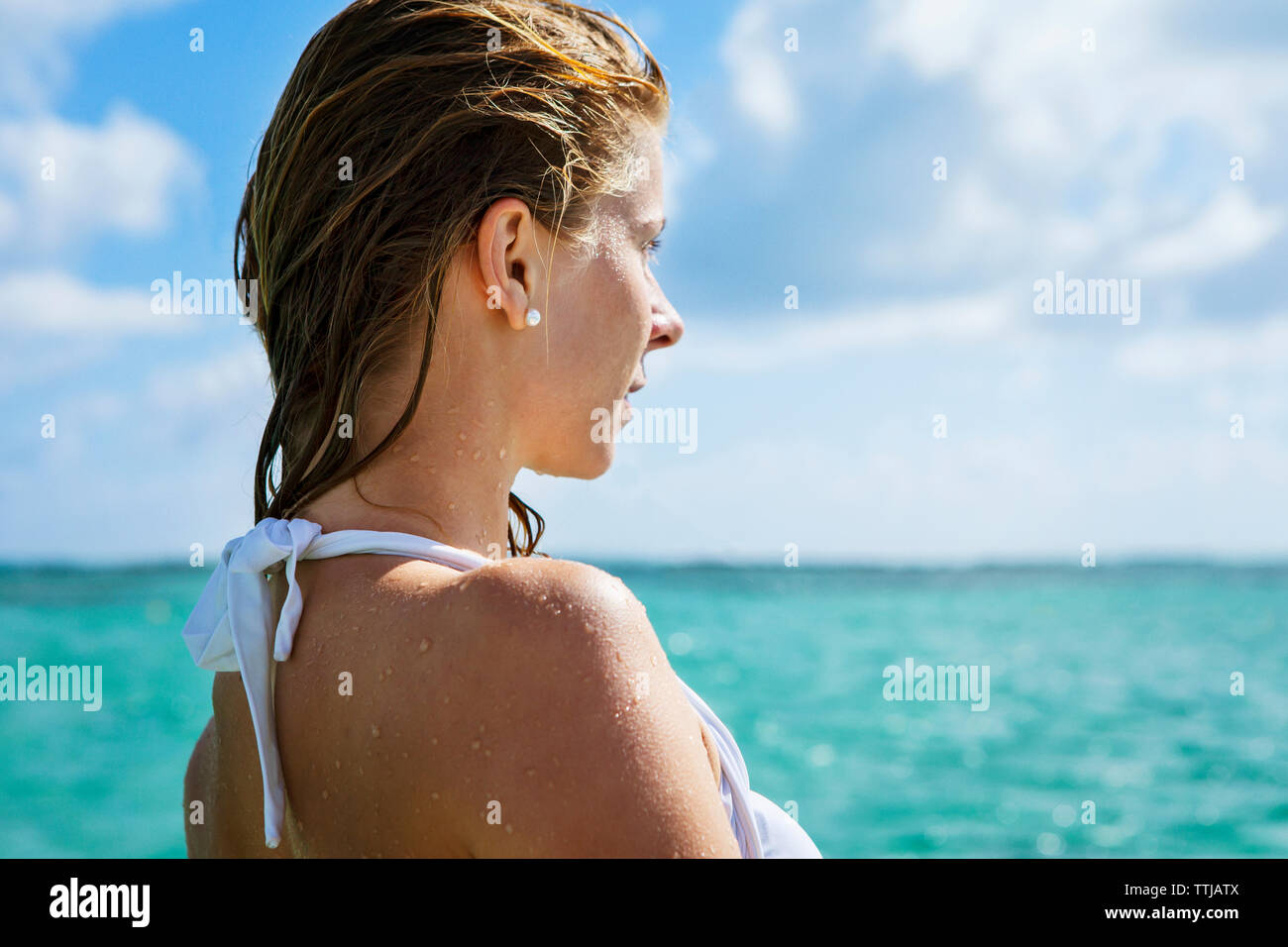 Side view of woman wearing bikini top against sky Stock Photo - Alamy