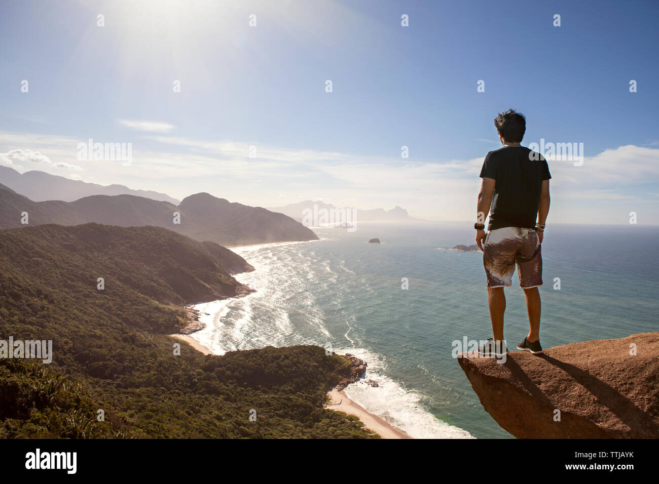 Rear view of hiker standing cliff by sea Stock Photo - Alamy