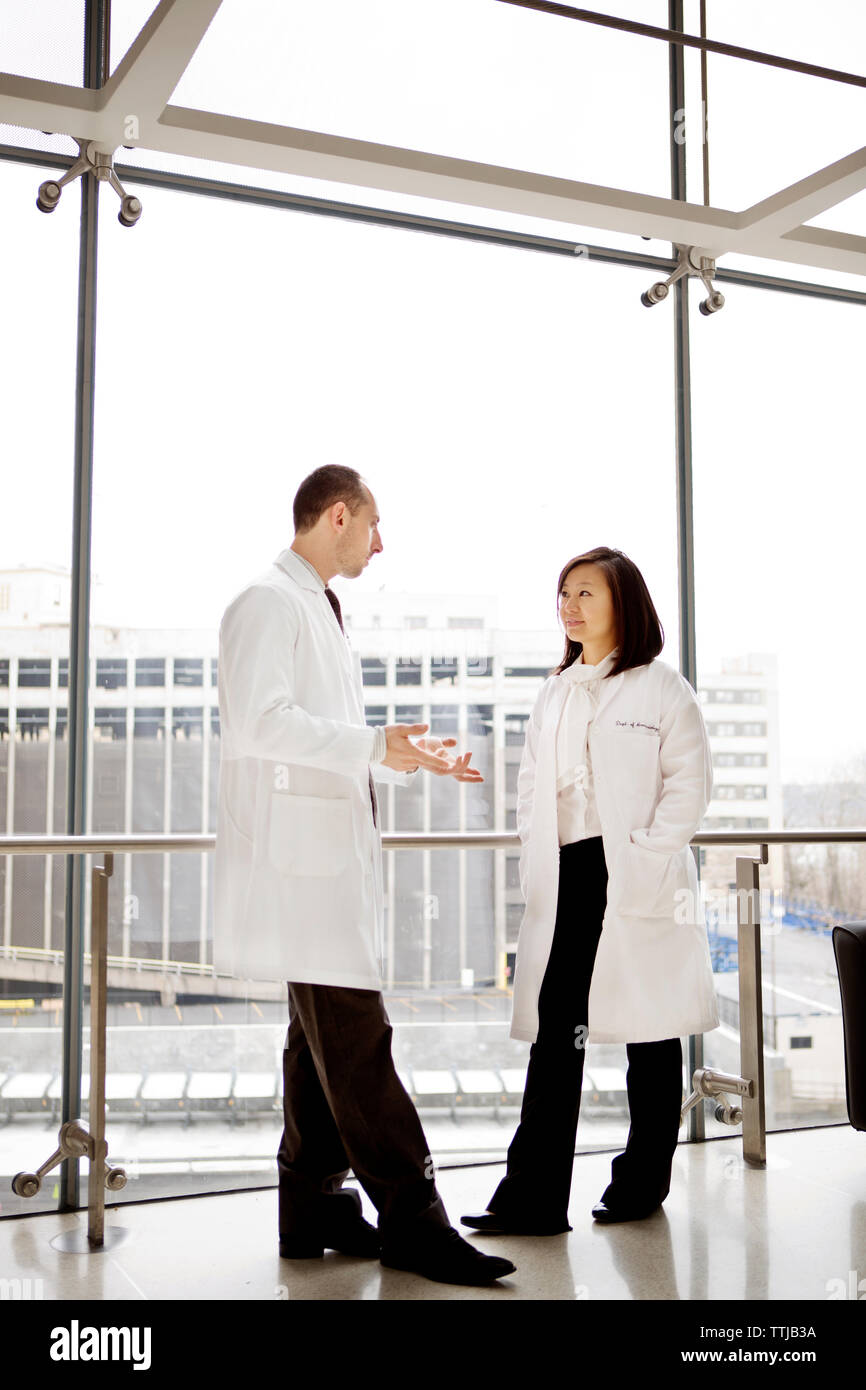 Doctors talking while standing by window in hospital Stock Photo - Alamy