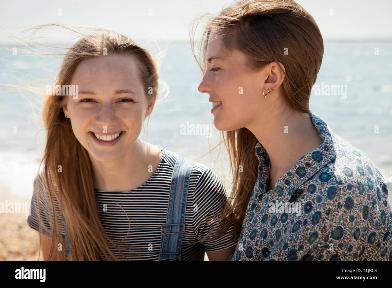 Portrait of smiling woman with friend on beach Stock Photo - Alamy