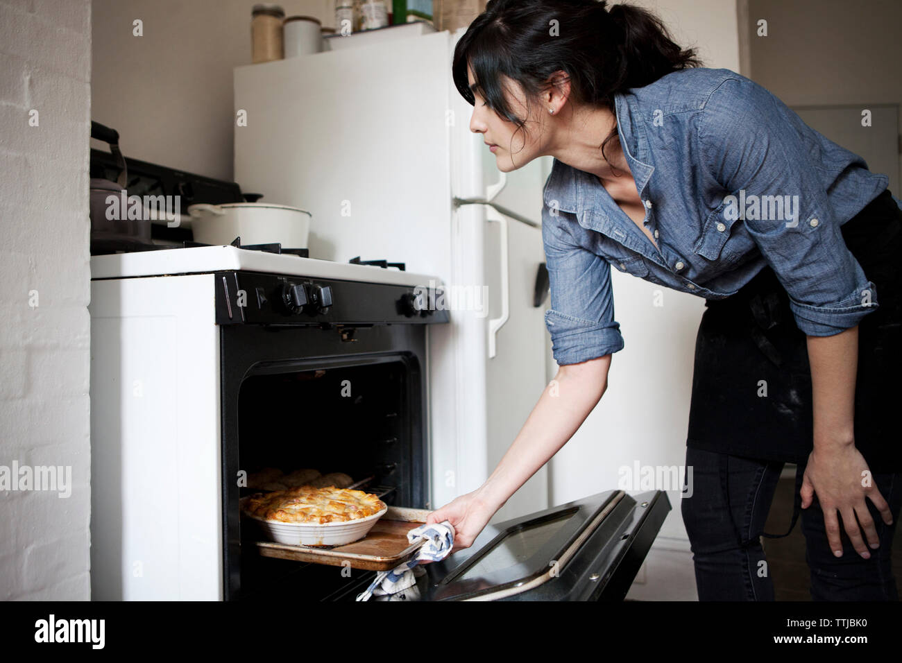 Woman removing pie from oven Stock Photo - Alamy