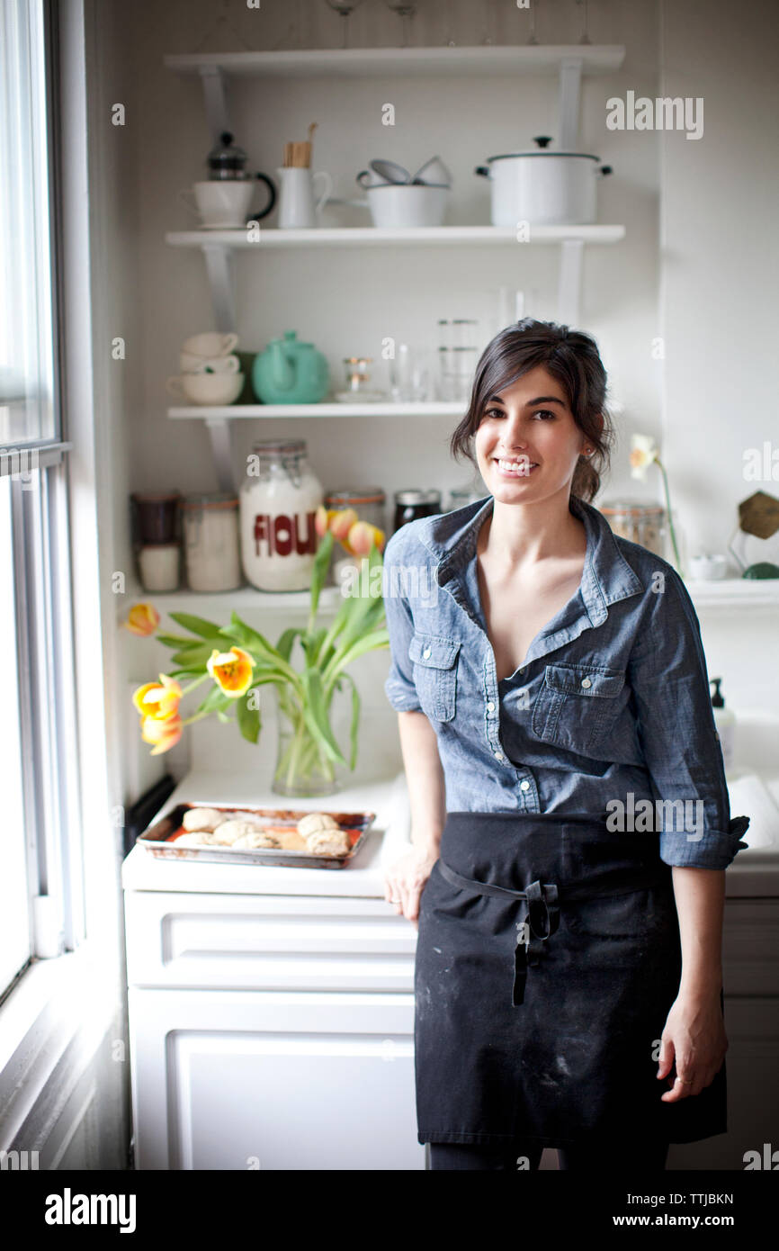 Portrait of woman standing by kitchen counter at home Stock Photo - Alamy