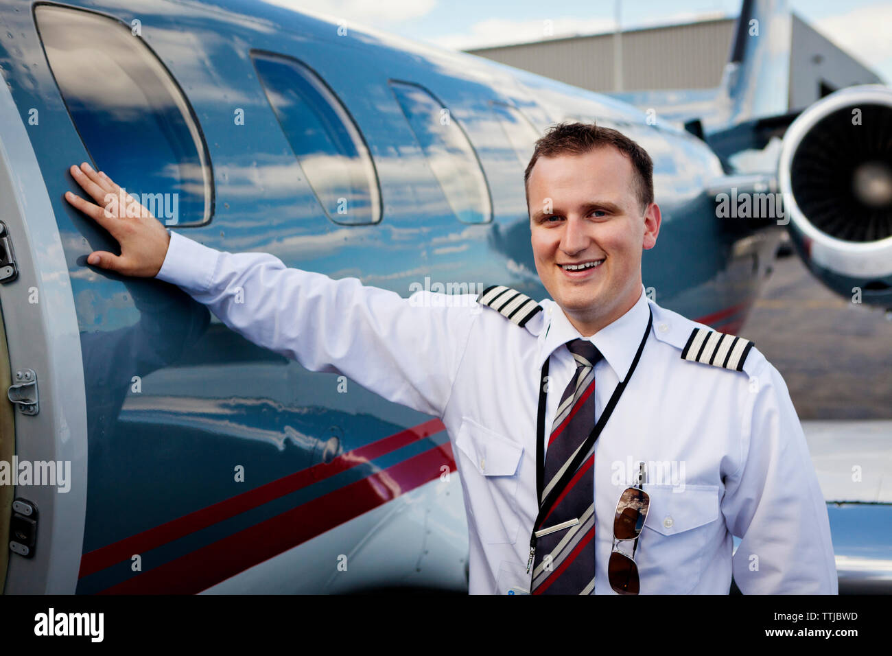 Portrait of happy pilot standing by airplane Stock Photo - Alamy