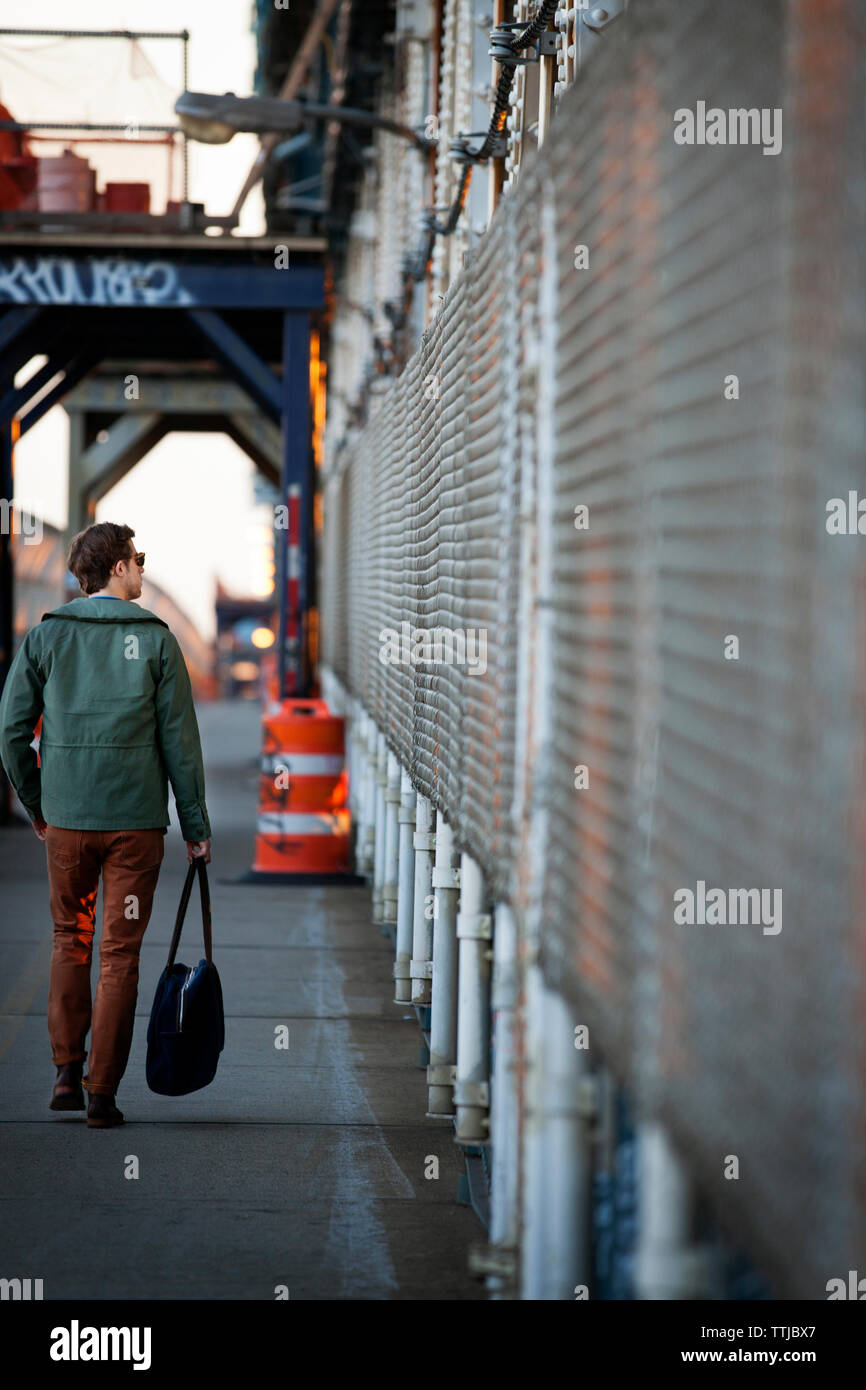 Rear view of man walking on pedestrian walkway of Manhattan Bridge ...