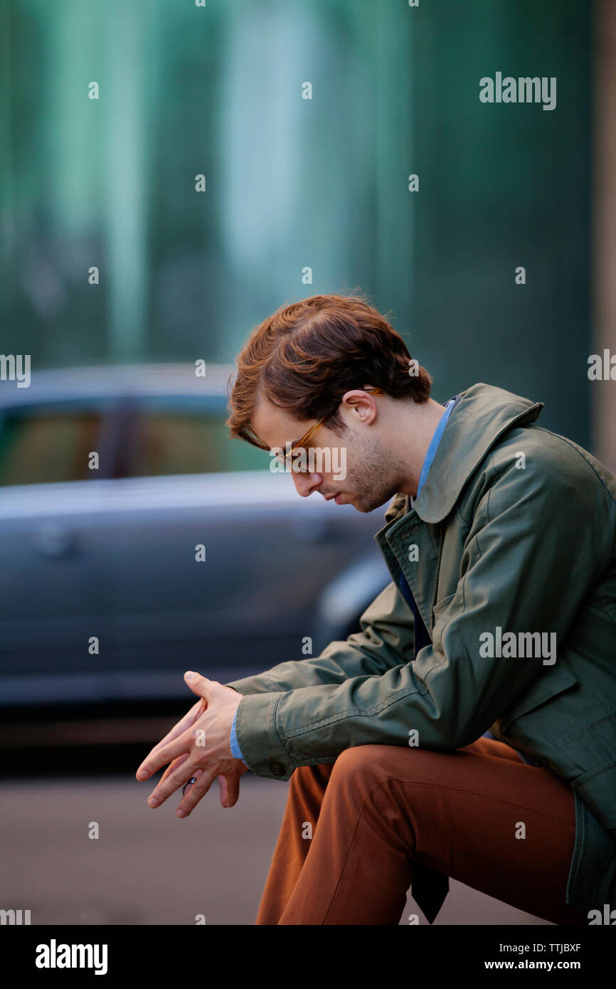 Side view of man sitting at street Stock Photo - Alamy