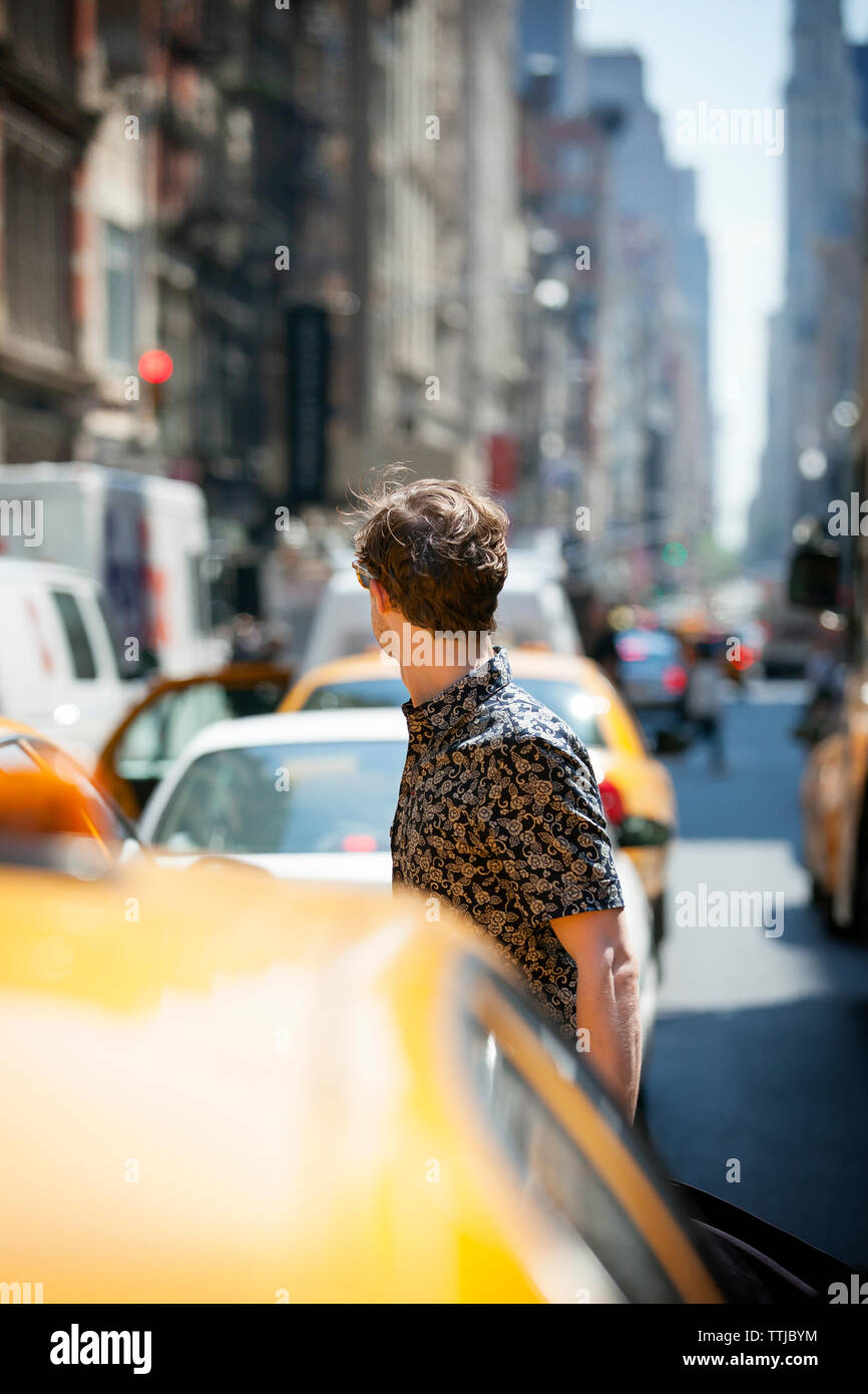 Side view of man standing by cars on road Stock Photo - Alamy