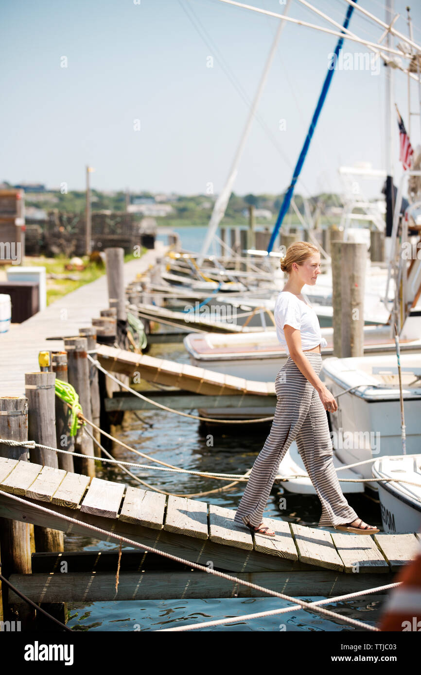 Side view of woman walking on jetty at harbor Stock Photo - Alamy