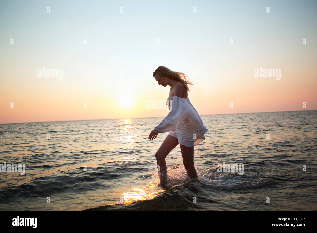 Side view of woman walking in water at beach against clear sky Stock ...